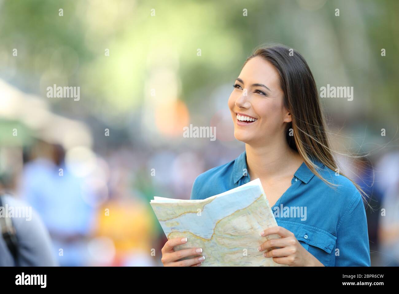 Happy tourist sightseeing and looking at side holding a guide on the ...