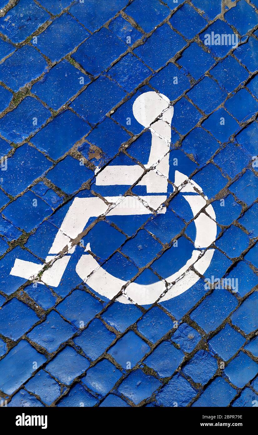 International handicapped symbol painted in bright blue on a paving ...