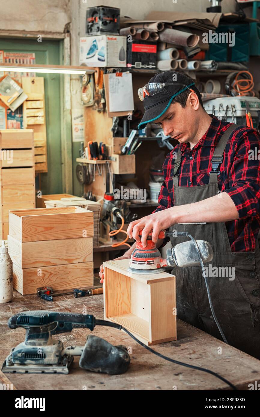 Worker grinds the wood box of angular grinding machine Stock Photo - Alamy