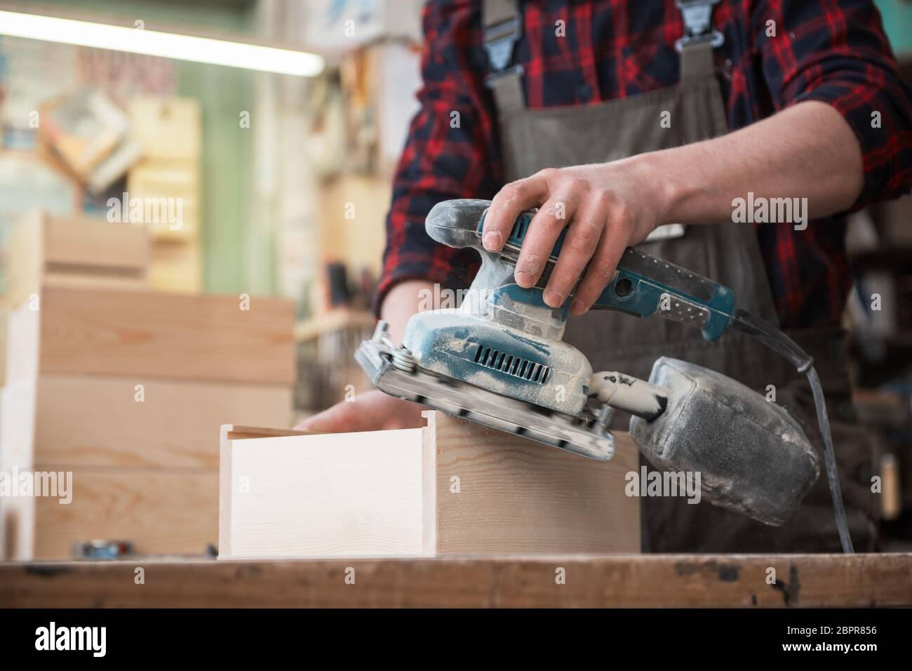 Worker grinds the wood box of angular grinding machine Stock Photo - Alamy