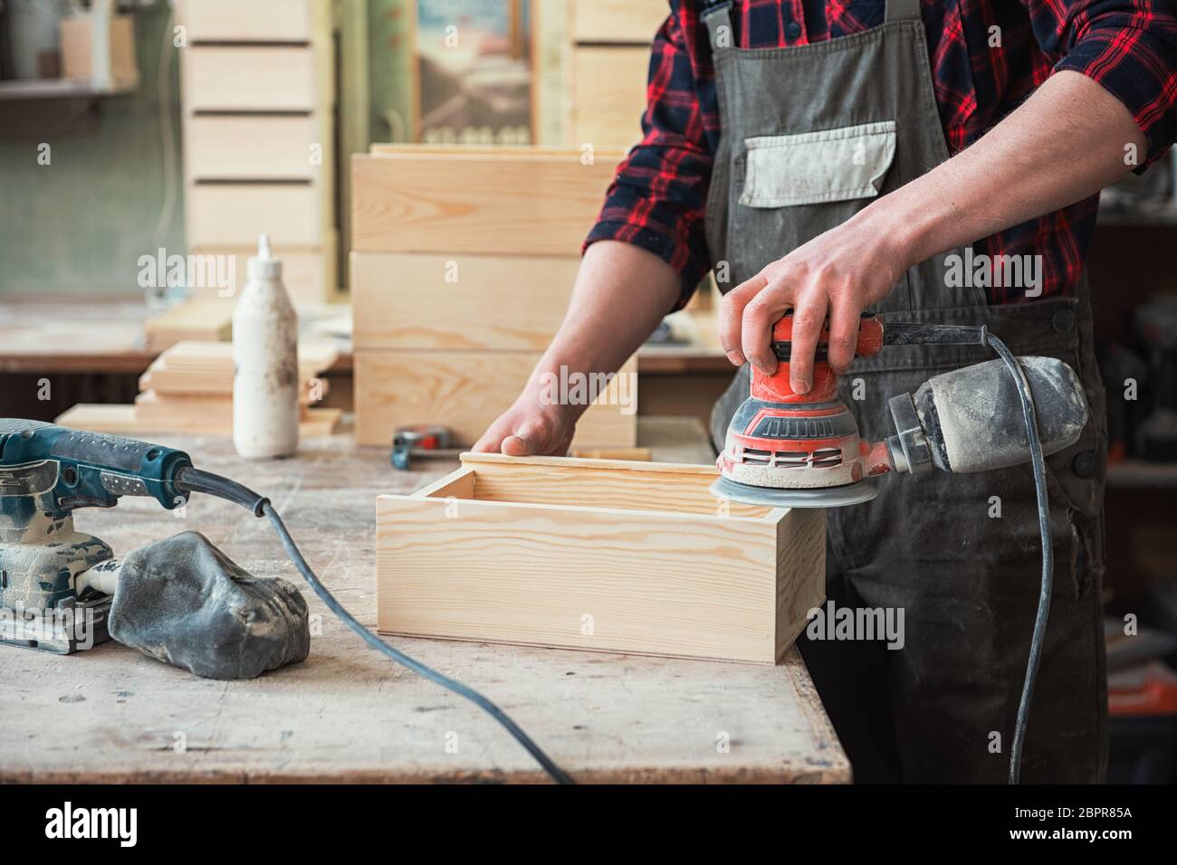 Worker grinds the wood box of angular grinding machine Stock Photo - Alamy