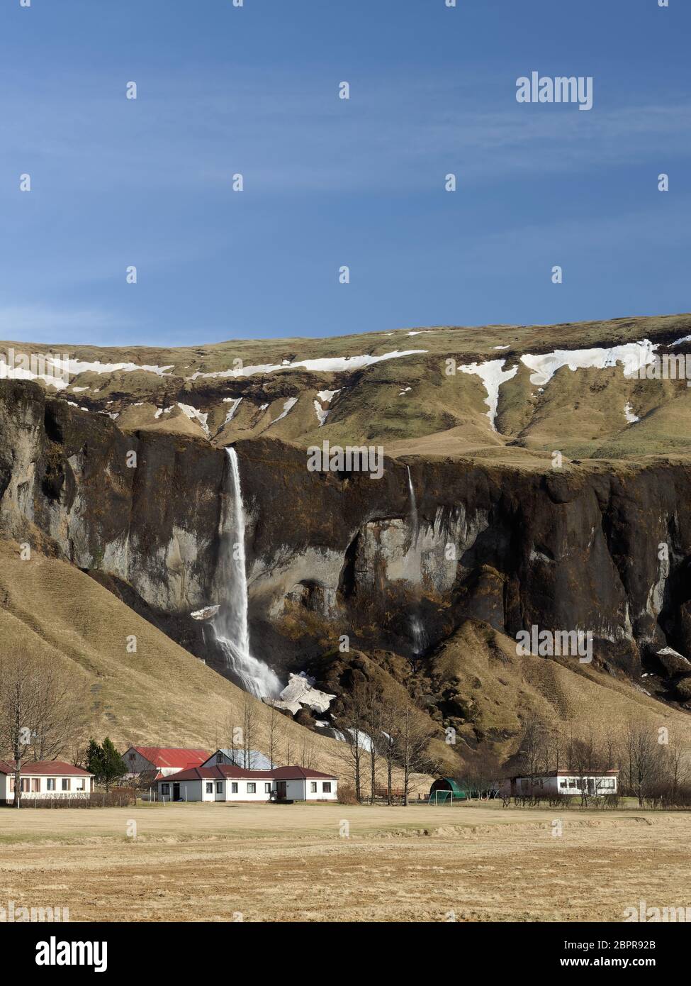 Basalt cliff, Foss a Sidu waterfall and farm, with blue sky in winter ...