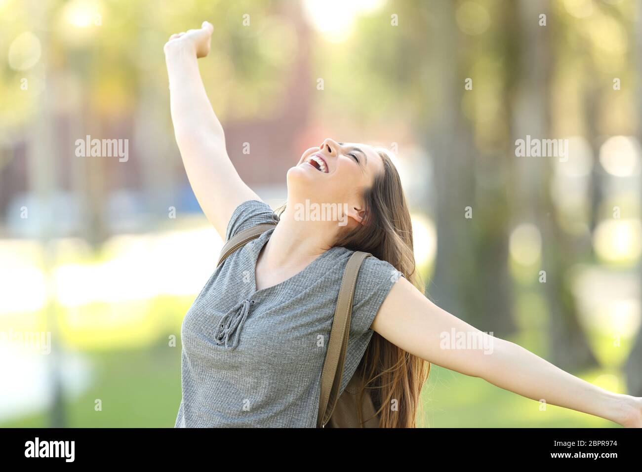 Excited happy girl raising arms in the street celebrating a good day ...