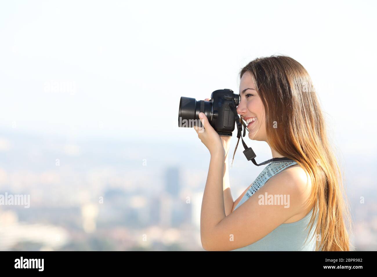 Side view portrait of a happy photographer taking photos with a dslr ...