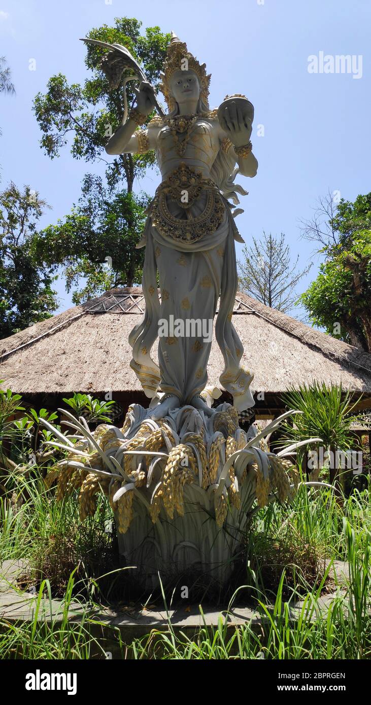 Traditional Bali god sculpture covered in front of blue sky and green ...