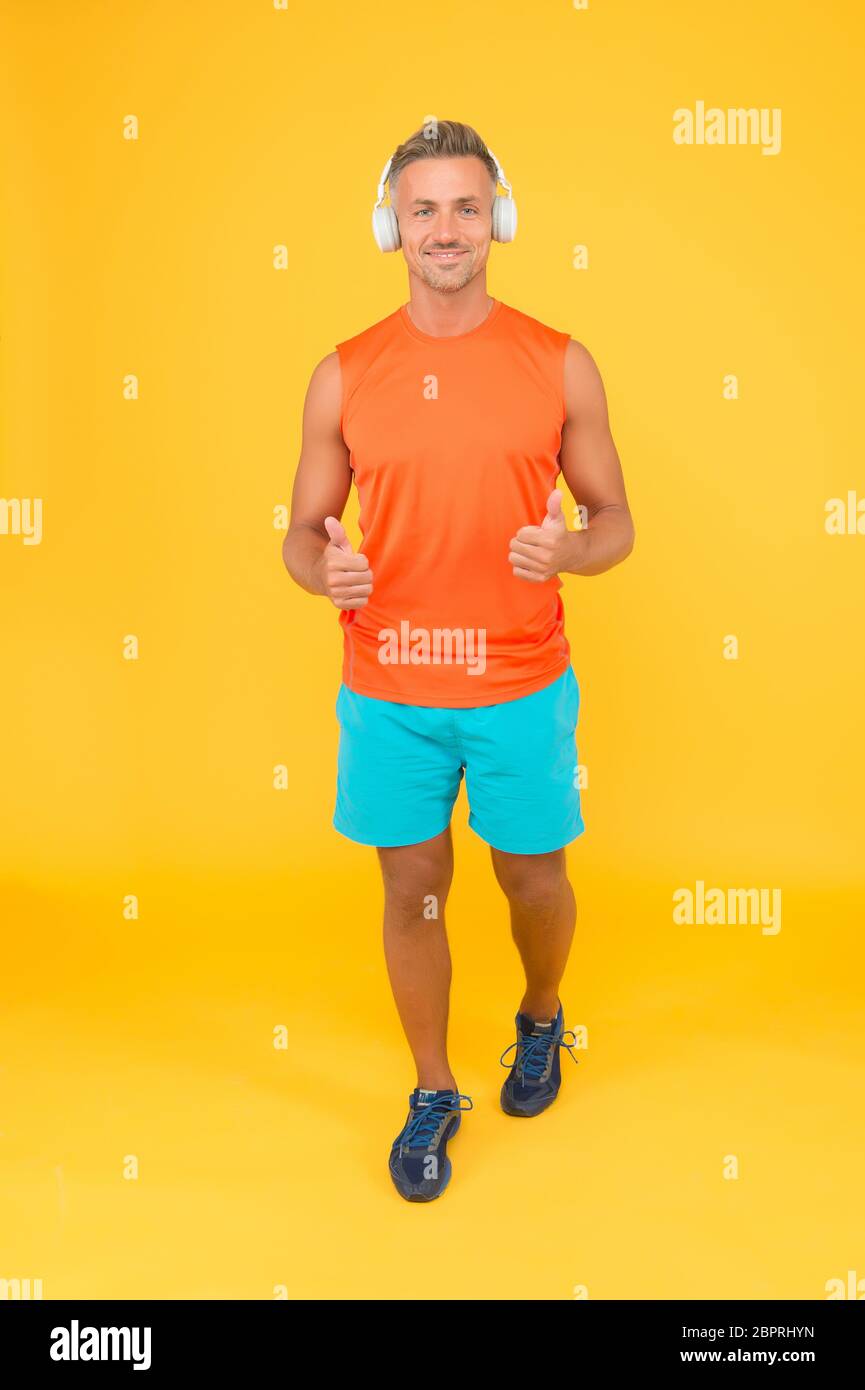 Promoting healthy lifestyle. Happy athlete in earphones give thumbs ups ...