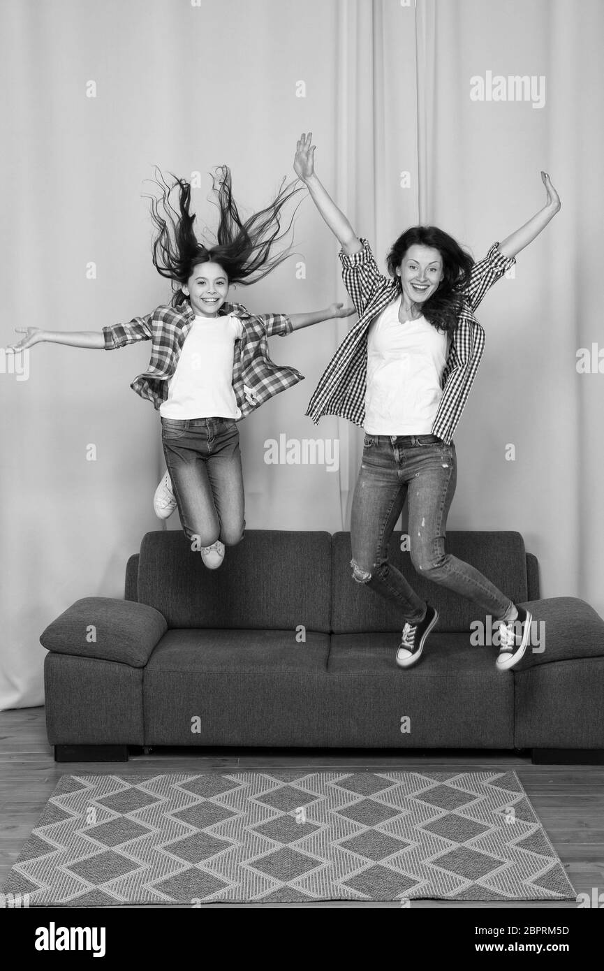 Fun leisure at home. girls party at home. happy sisters jump in freedom ...