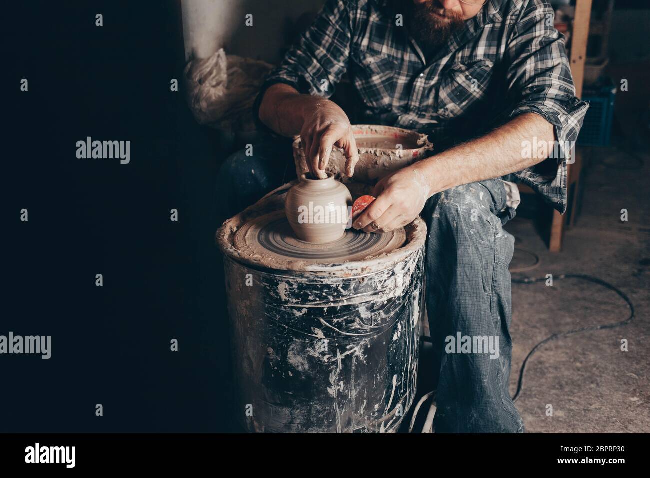 Man works on the potter's wheel creating a jug of clay Stock Photo - Alamy
