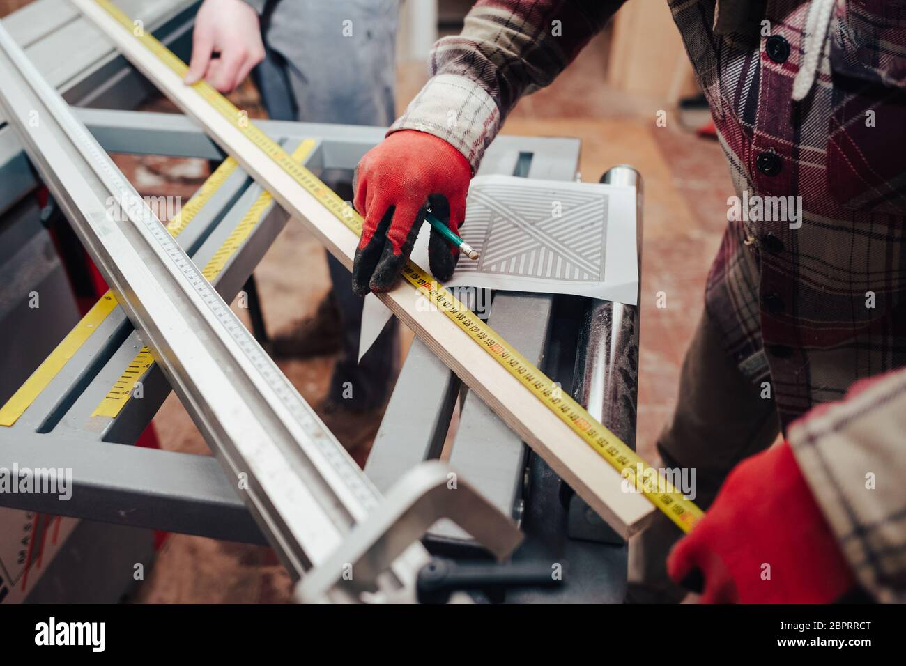 Worker marks with pencil a plywood for cutting on a circular saw Stock ...