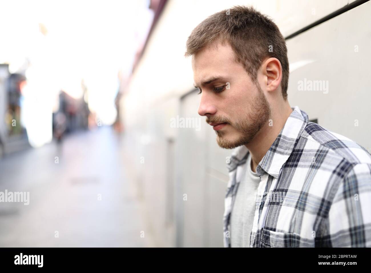 Side view portrait of a sad man complaining alone in the street Stock ...