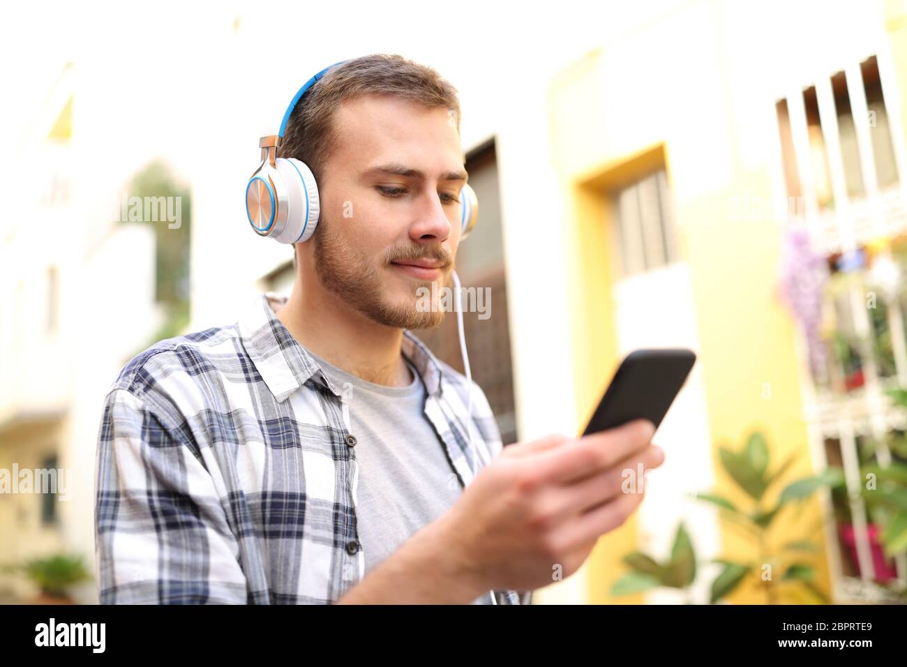 Serious man listening to music on smart phone watching content walking ...