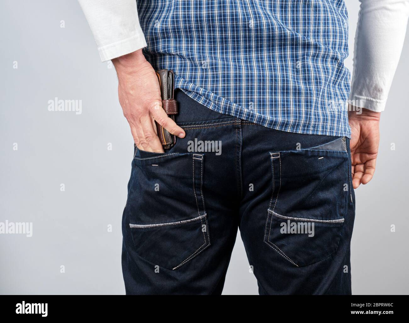 man in a blue plaid shirt and jeans puts a leather wallet in his back ...