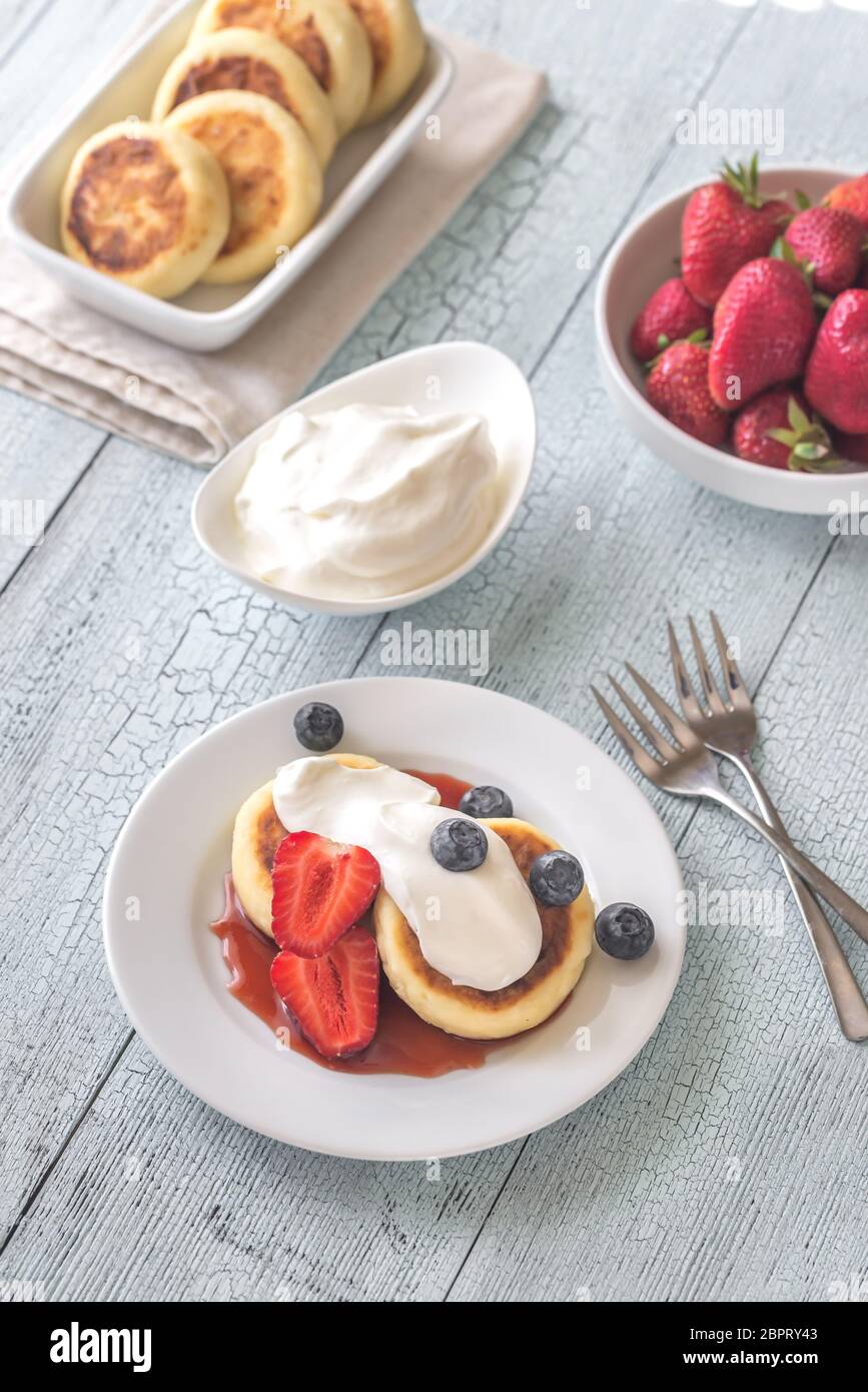 Cottage cheese patties with whipped cream and berry syrup Stock Photo ...