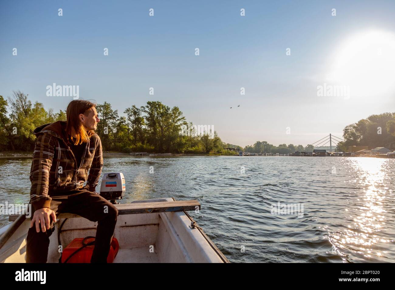 Sad and pensive mid age man with long brown hair is on his white boat ...