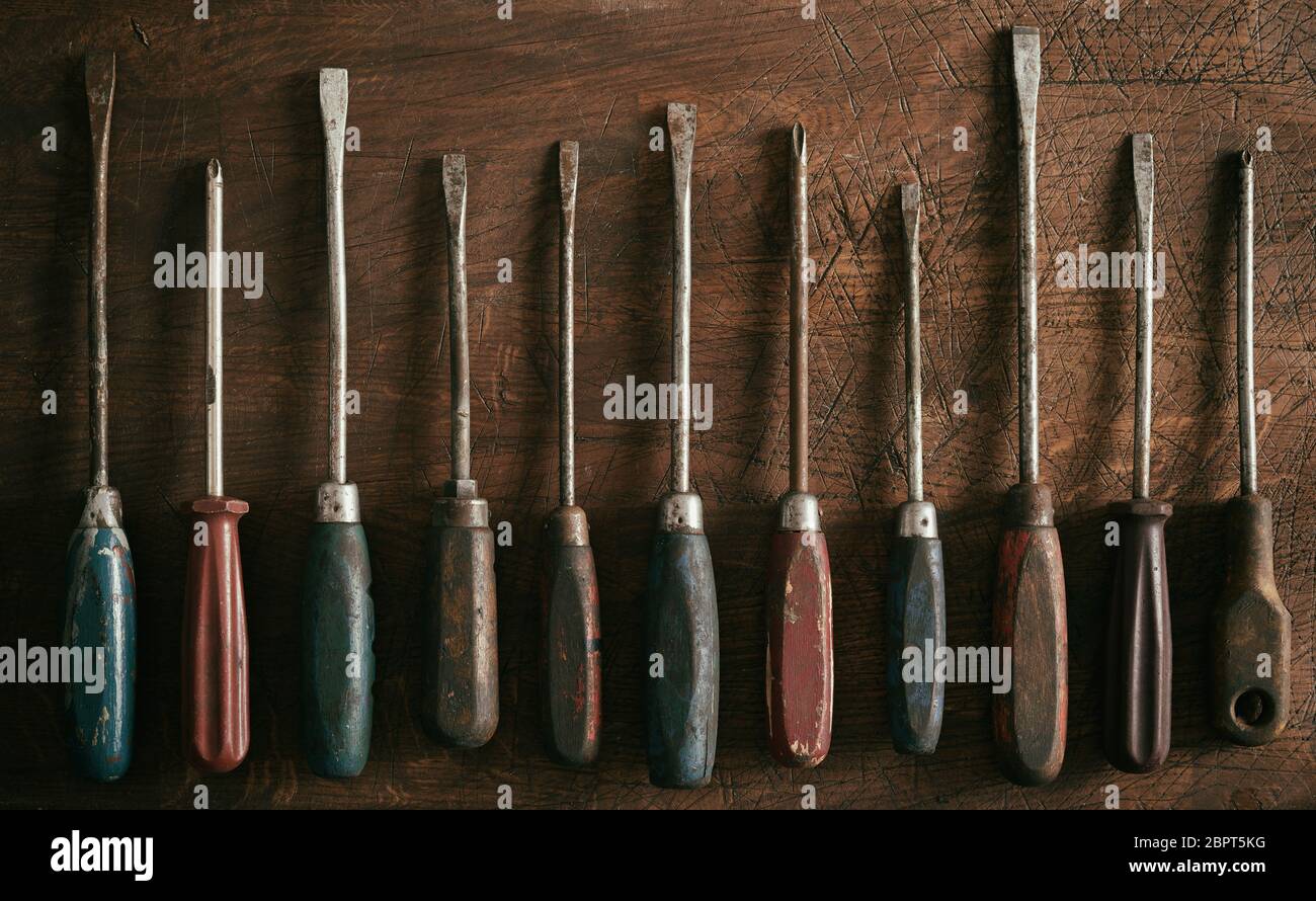 Neat row of old worn vintage screwdrivers with wooden handles on a ...