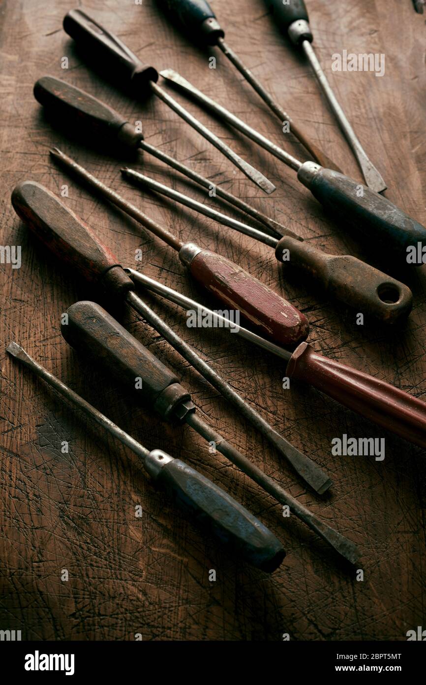 Dark moody still life of vintage screwdrivers with dirty worn wooden ...
