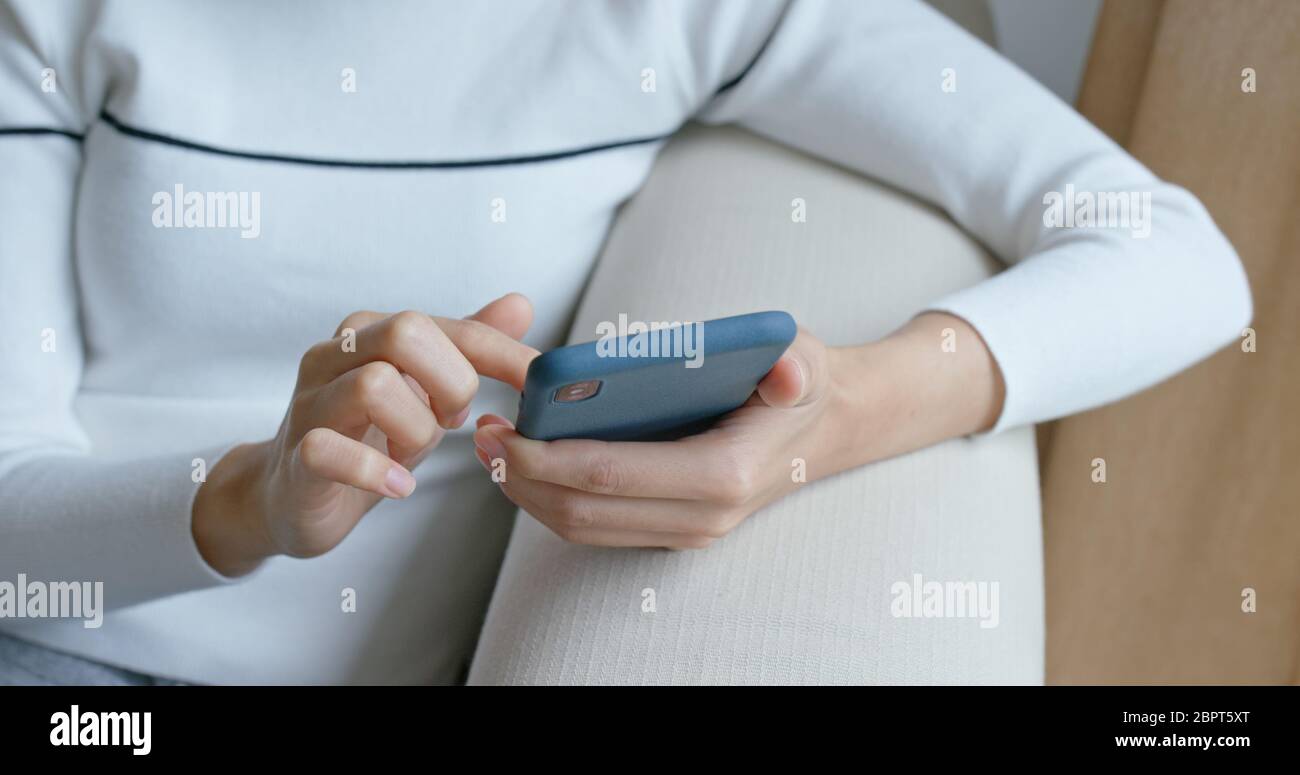 Woman use of smart phone and sit on the sofa Stock Photo - Alamy