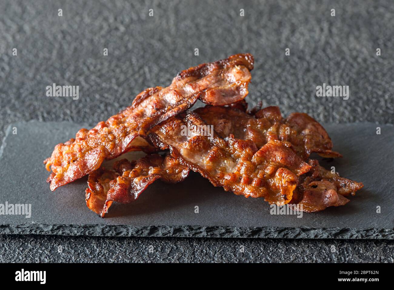 Fried bacon strips on the stone dark board Stock Photo - Alamy