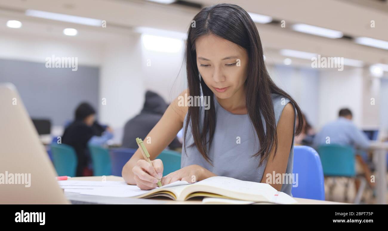 Woman writing on note in university library Stock Photo - Alamy