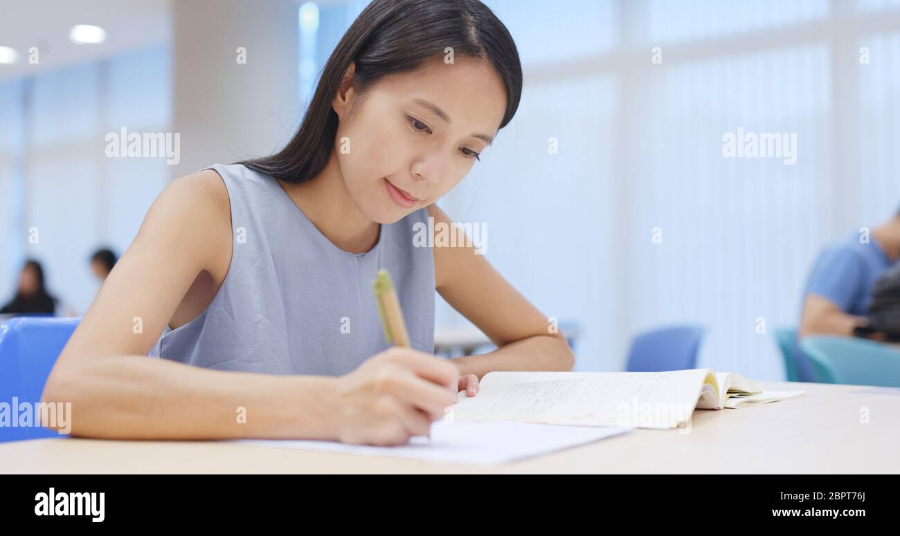 Young Woman doing homework at university library Stock Photo - Alamy