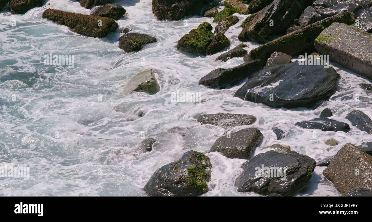 Breaking waves beating and rolling stones at sea coast Stock Photo - Alamy