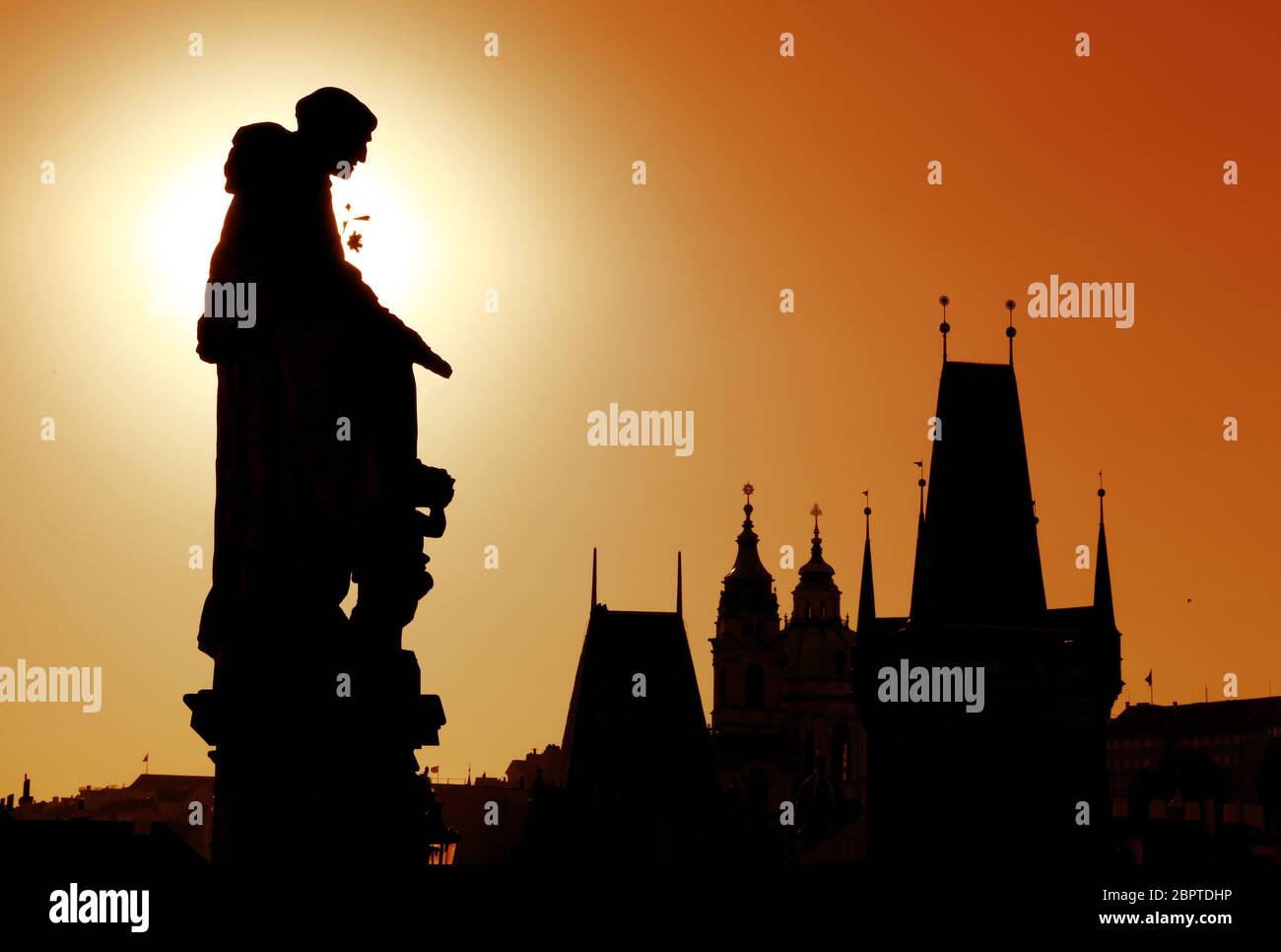 Sunset backlit silhouettes of statues and roofs of cityscape skyline at ...