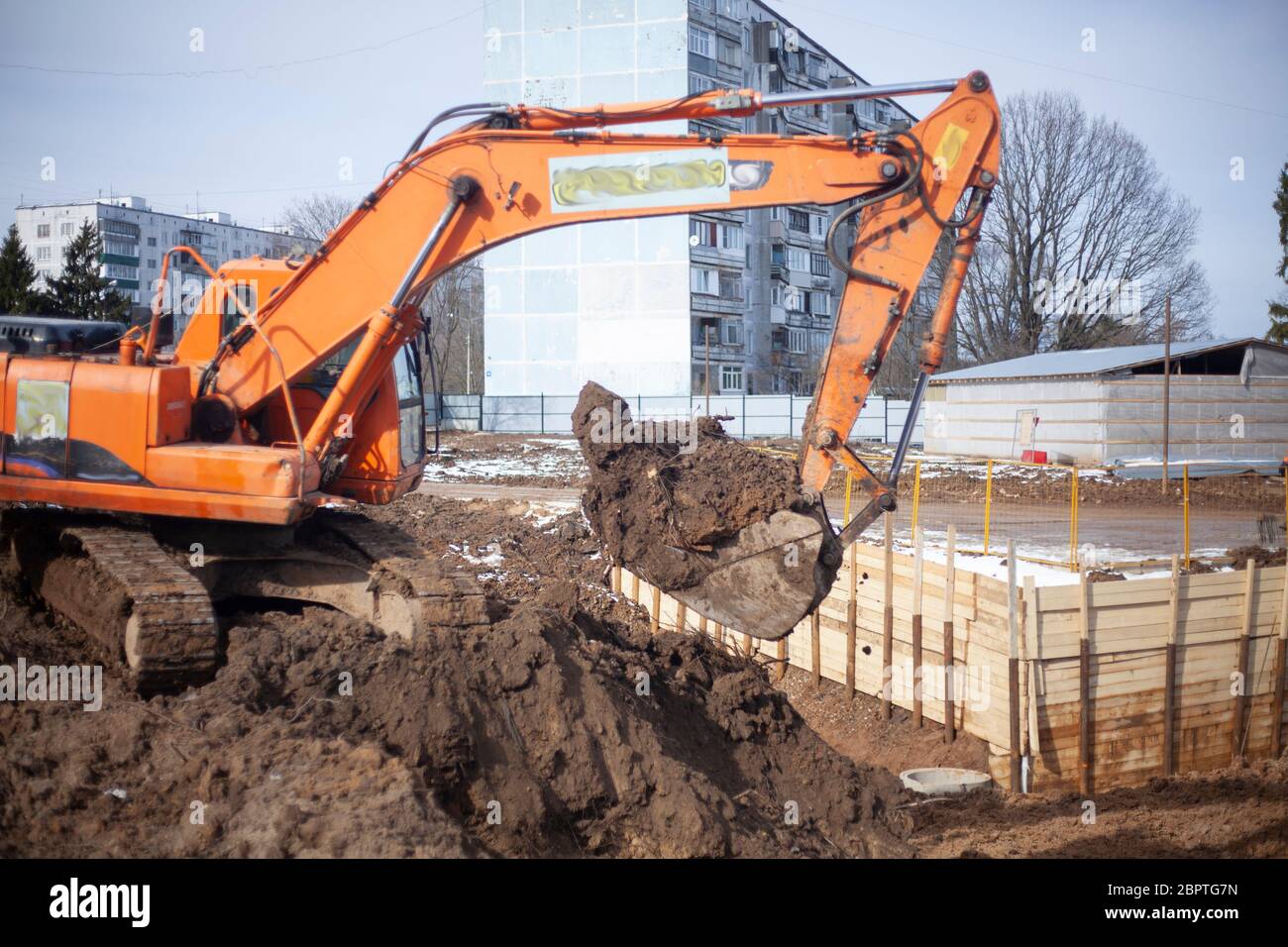 A machine at a construction site digs the ground. An escalator is ...