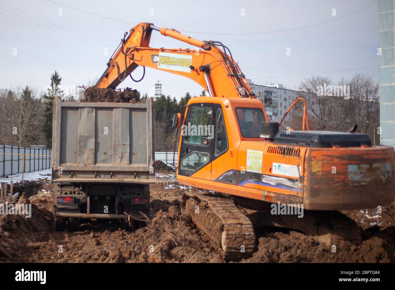 A machine at a construction site digs the ground. An escalator is ...