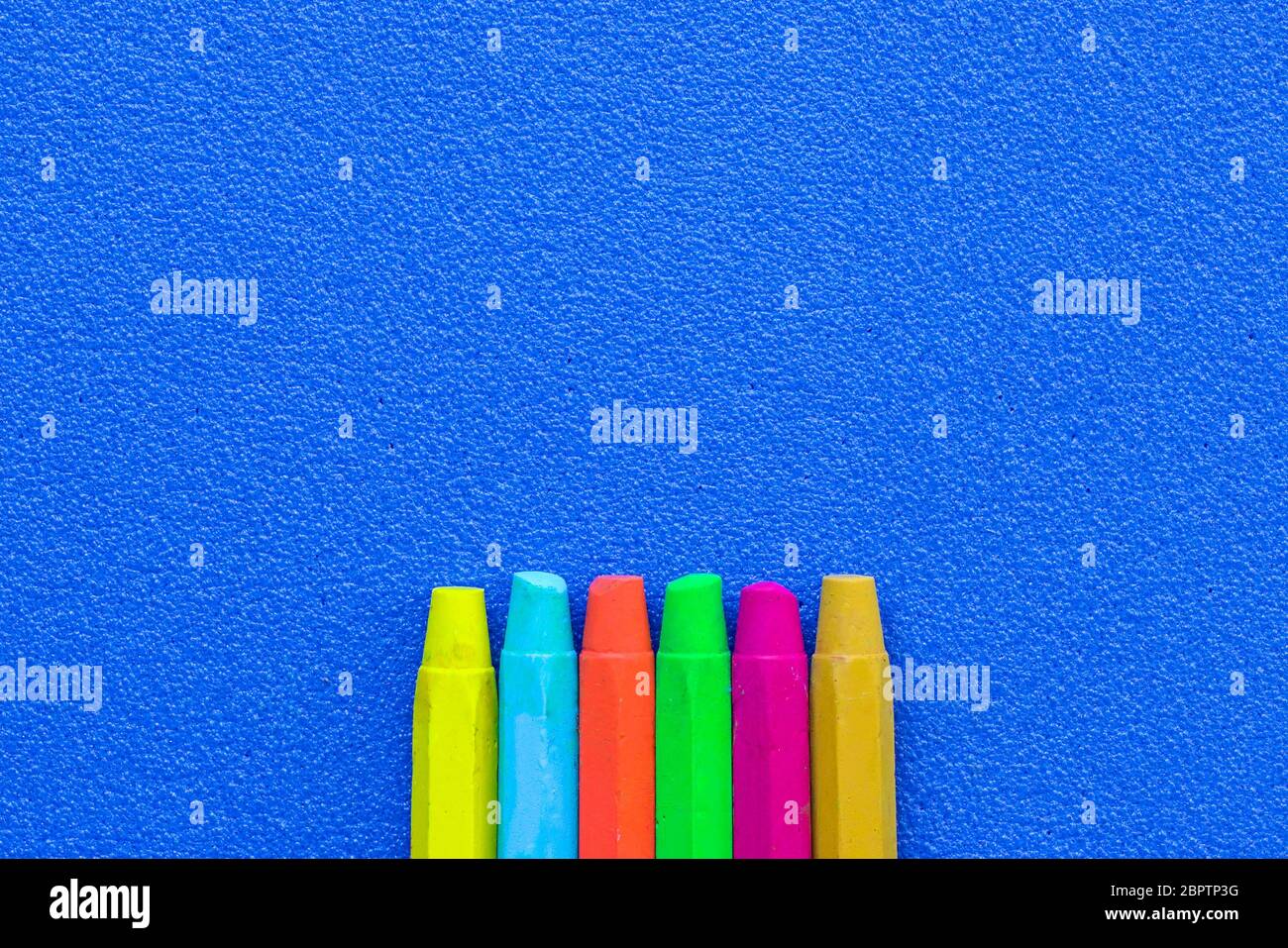 Multi-colored crayons on blue board. Top view. Copy space. Early ...