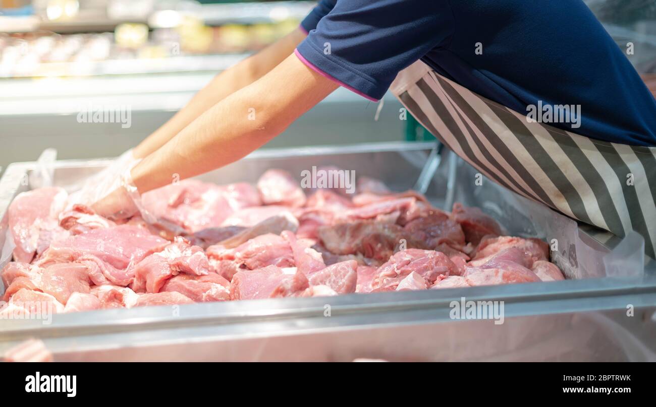 The supermarket employee preparing the Fresh pork meat slice on display ...