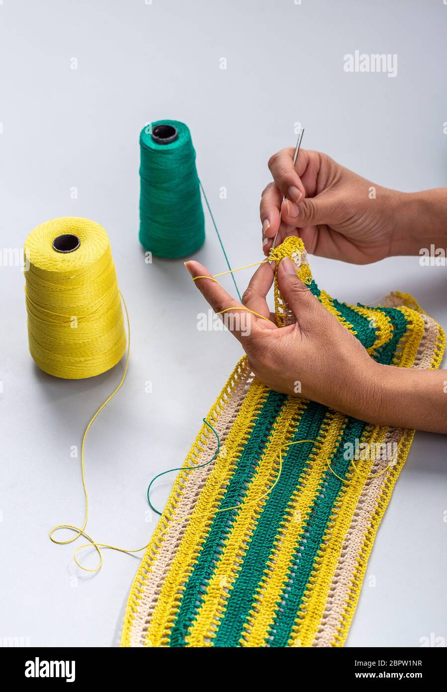 a woman making a thread pattern with yellow and green threads using ...