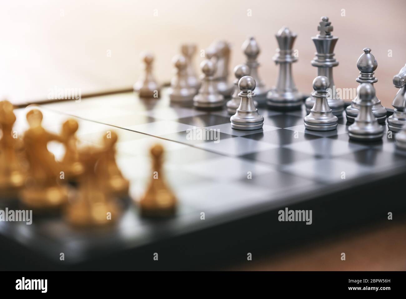 Closeup image of a silver and golden color chess set on chessboard ...