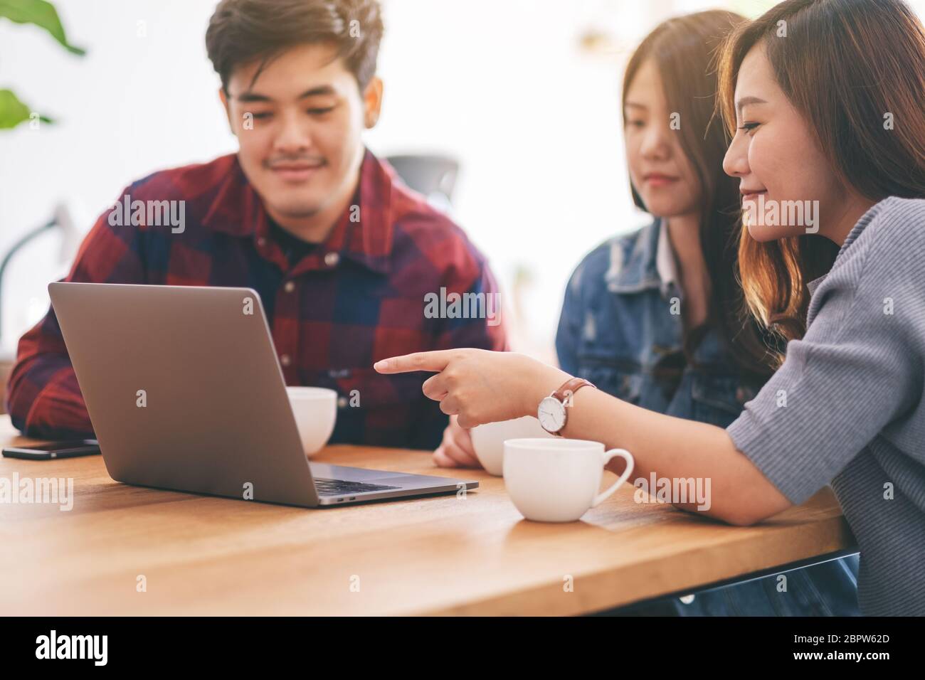 Three young asian people using and looking at the same laptop computer ...