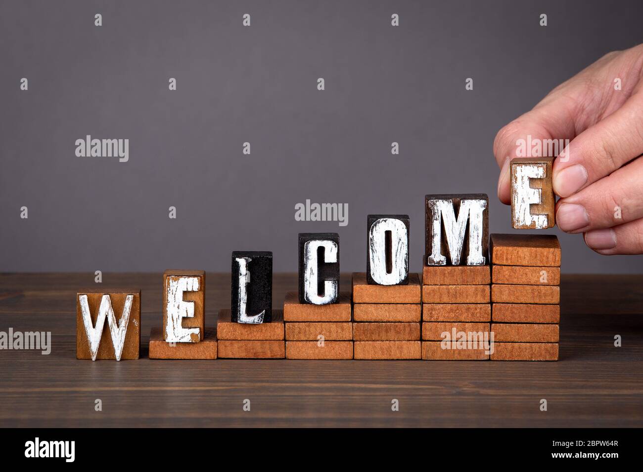 WELCOME concept. Wooden alphabet letters on steps. Gray background ...