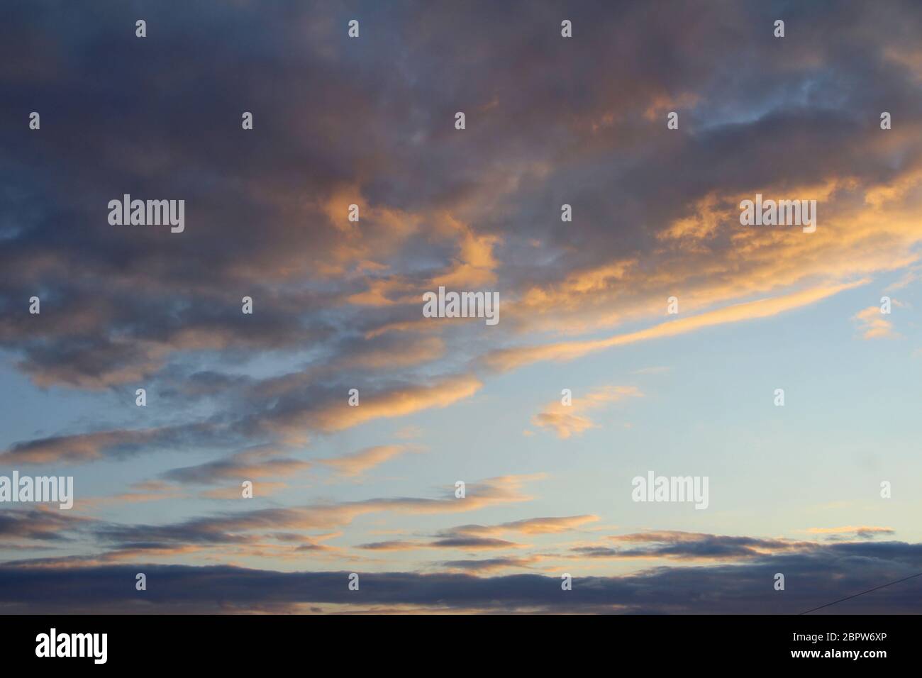 Clouds in the sky are illuminated from below by the red light of the ...