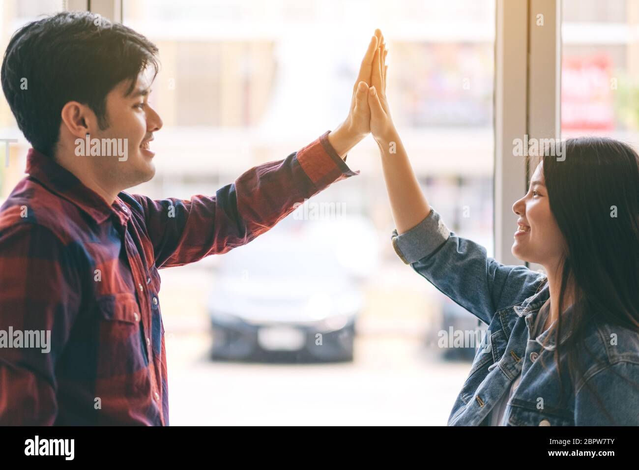 A young couple putting their hands to make high five to each other ...