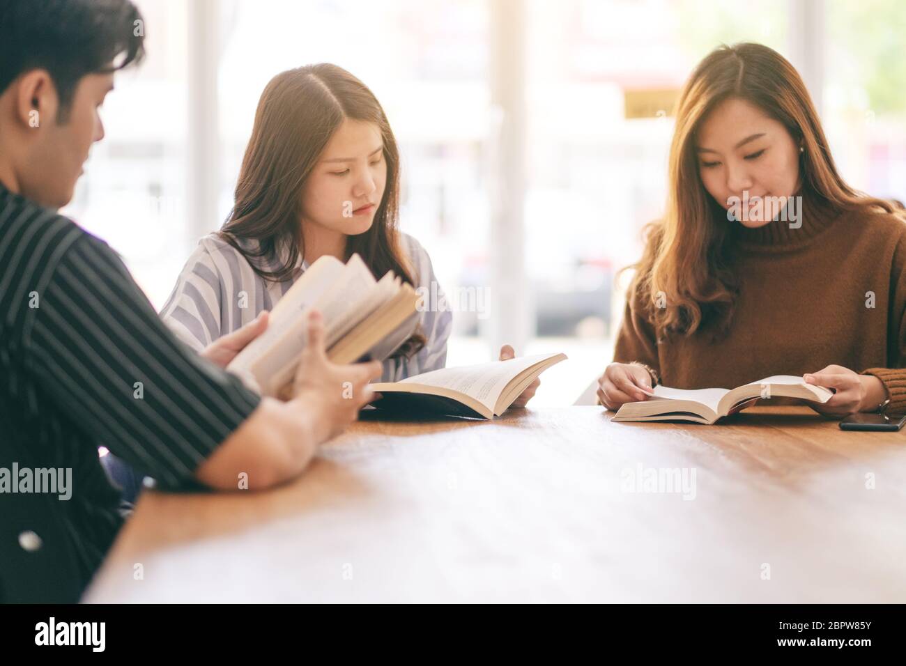 Group of people sitting and enjoyed reading book together on wooden ...