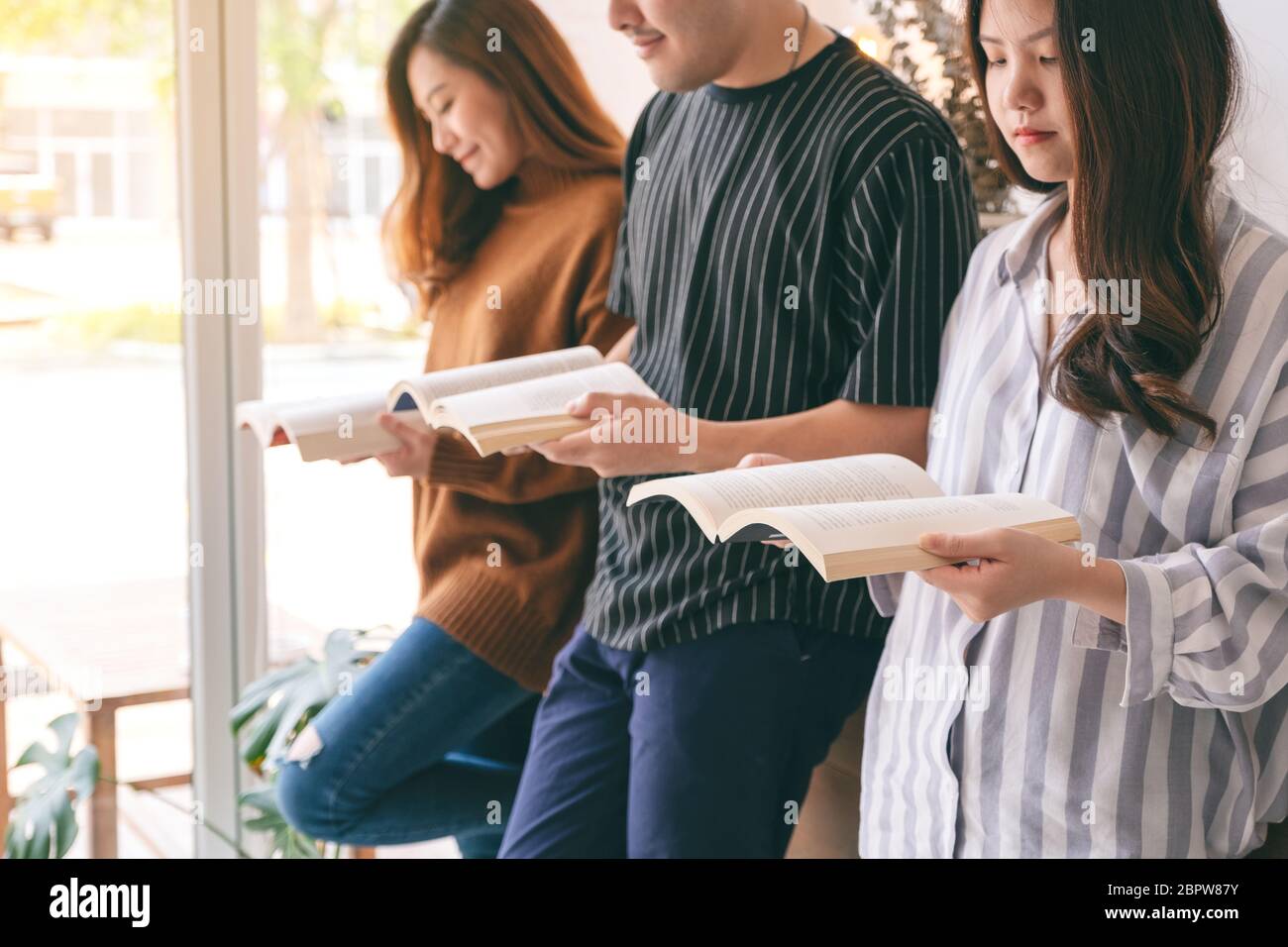 Three young people enjoyed reading books together Stock Photo - Alamy