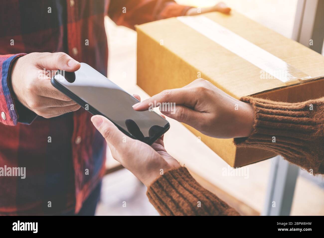 woman receiving parcel box and signing name on the phone from delivery ...