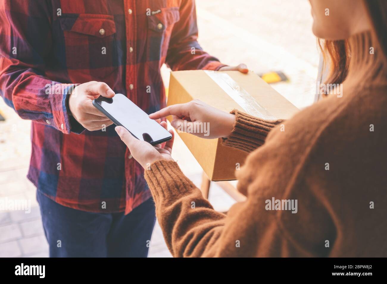 woman receiving parcel box and signing name on the phone from delivery ...