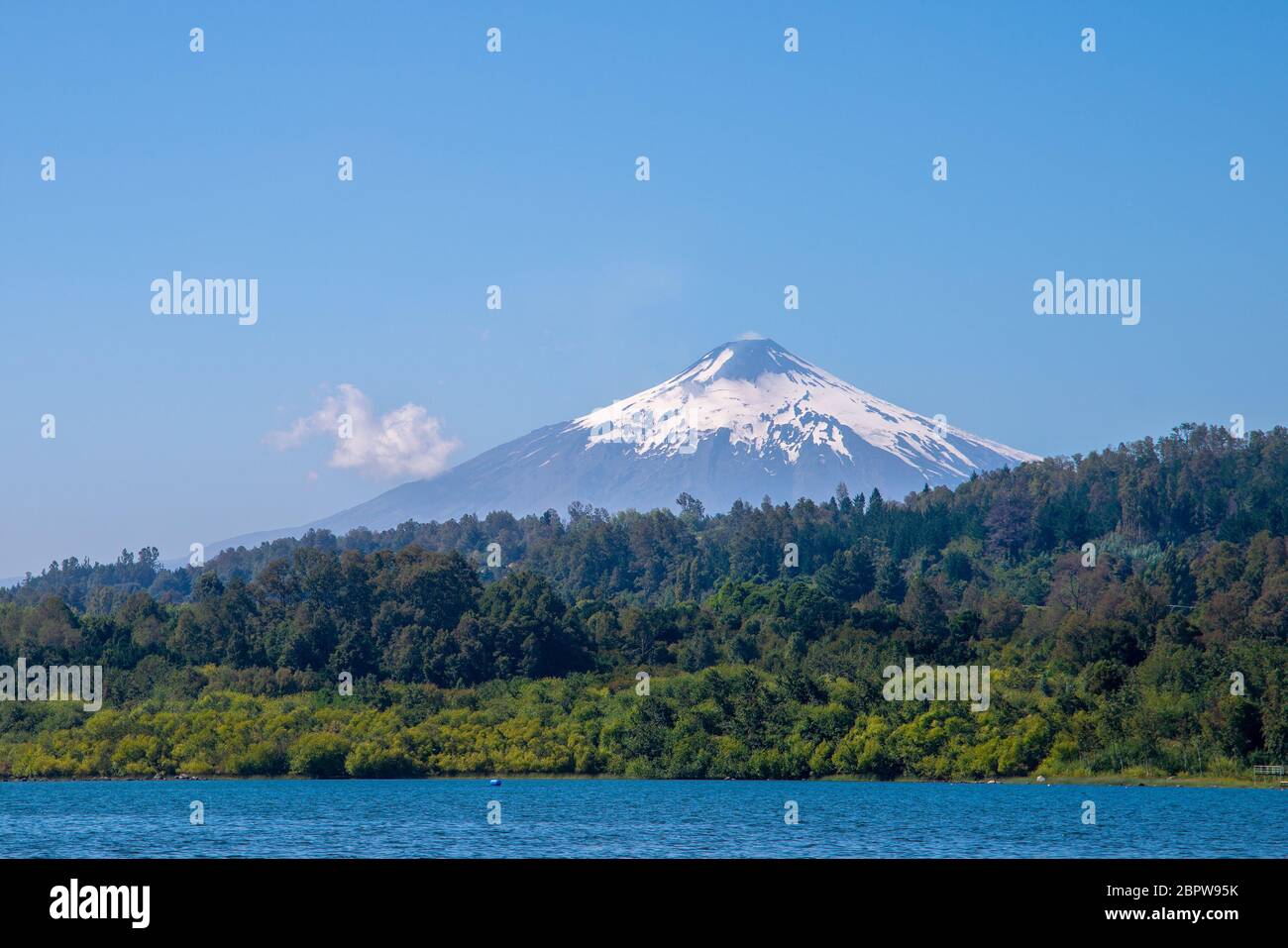 Villarrica volcano with a snow-capped peak against a blue sky. View ...