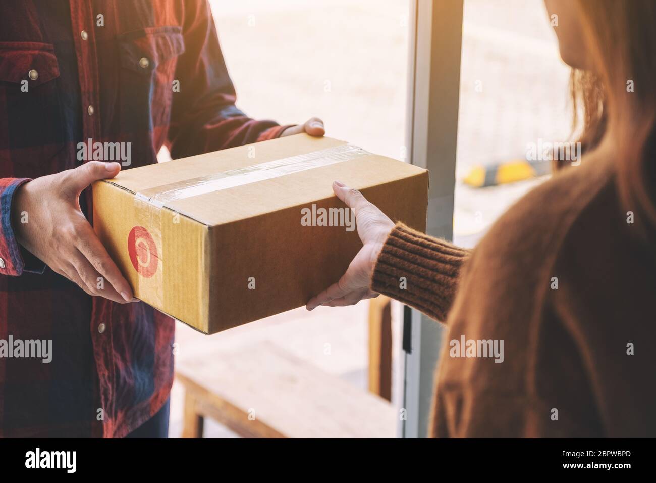 Delivery woman giving carton postal hi-res stock photography and images ...