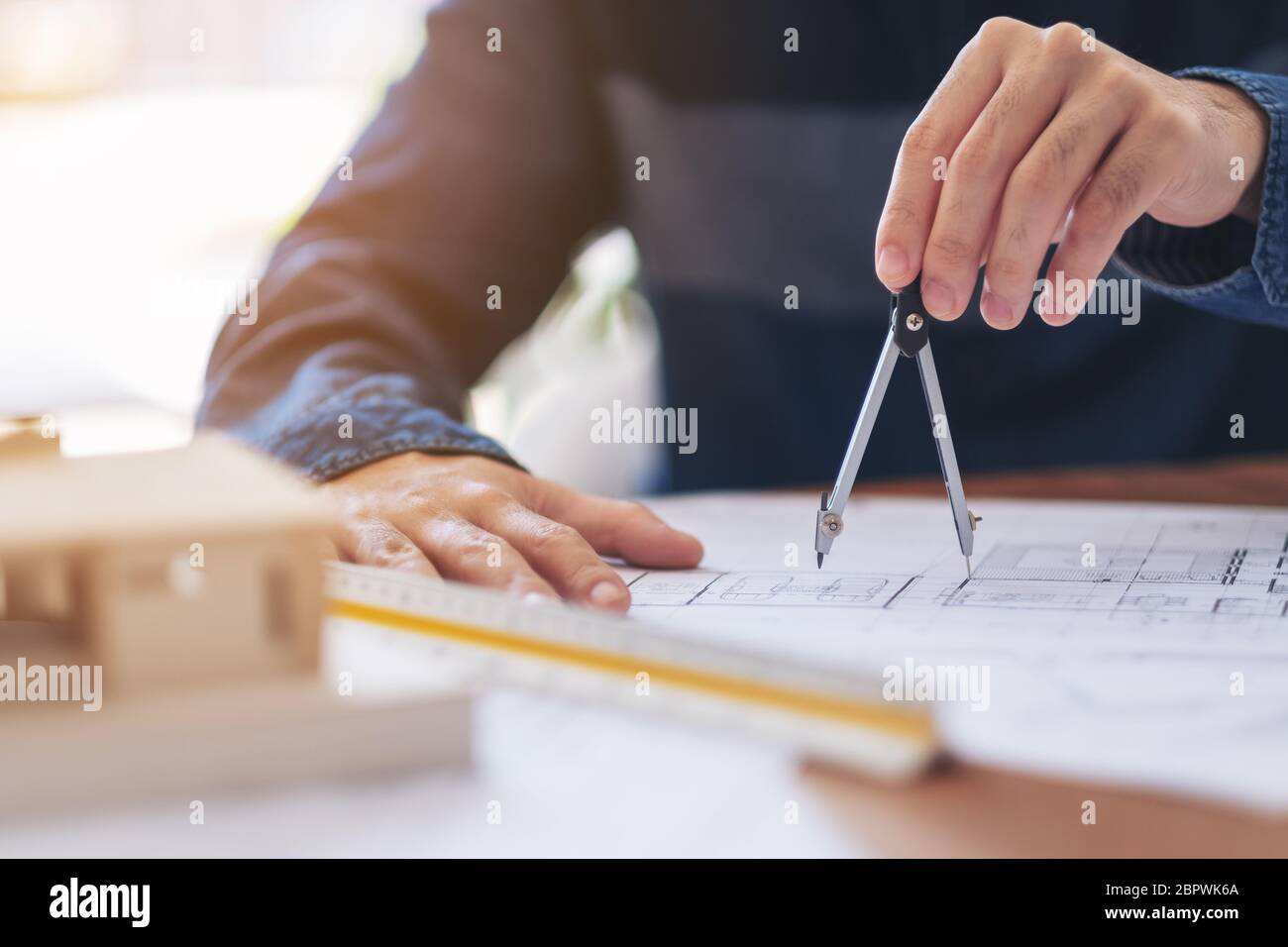 An architect using compass to draw and measure shop drawing in office ...