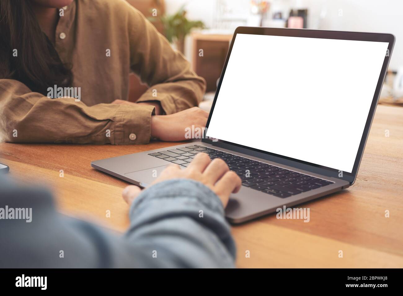 People using and looking at mockup laptop computer on wooden table ...