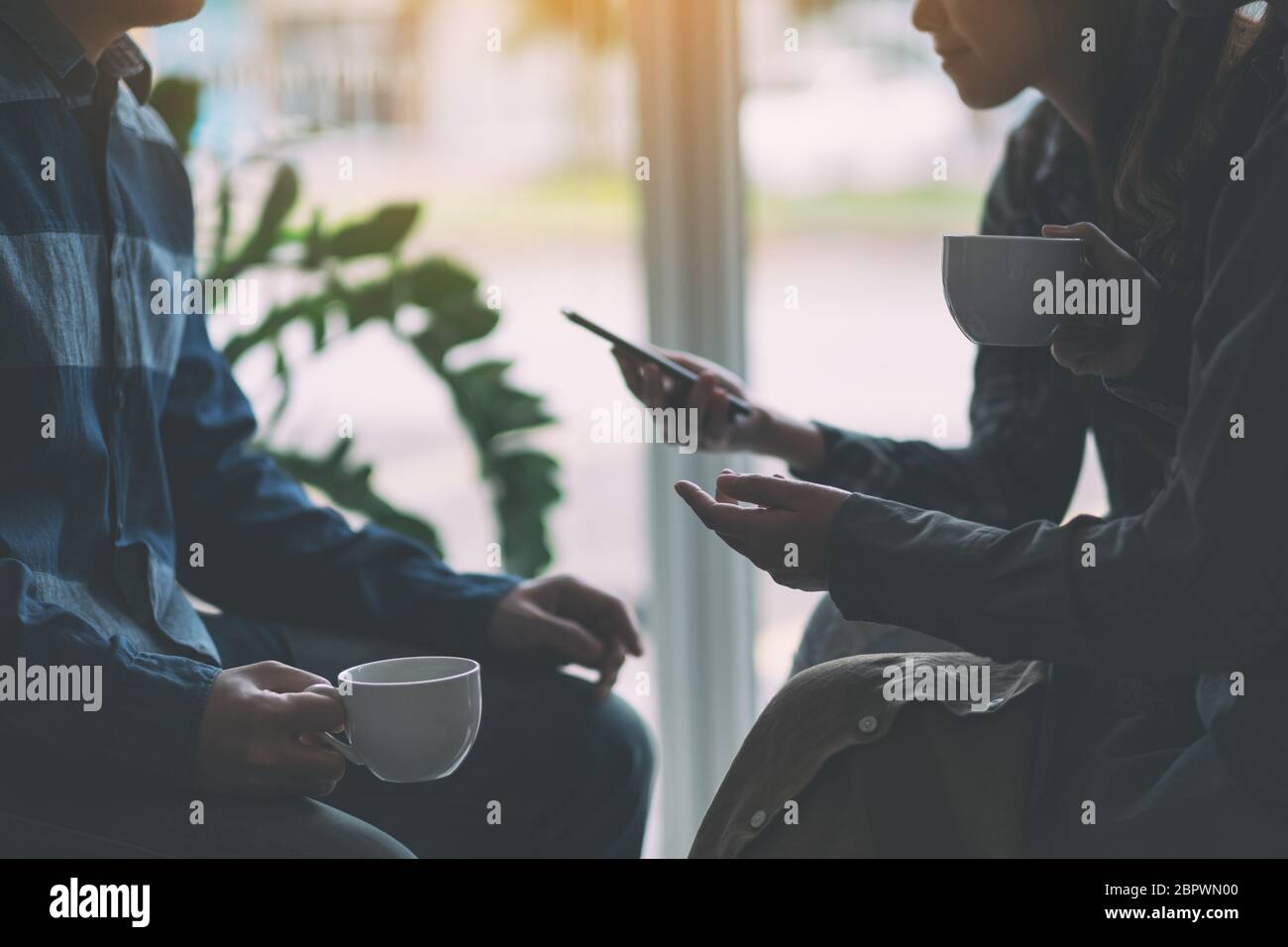 People using phone, talking and drinking coffee together Stock Photo ...