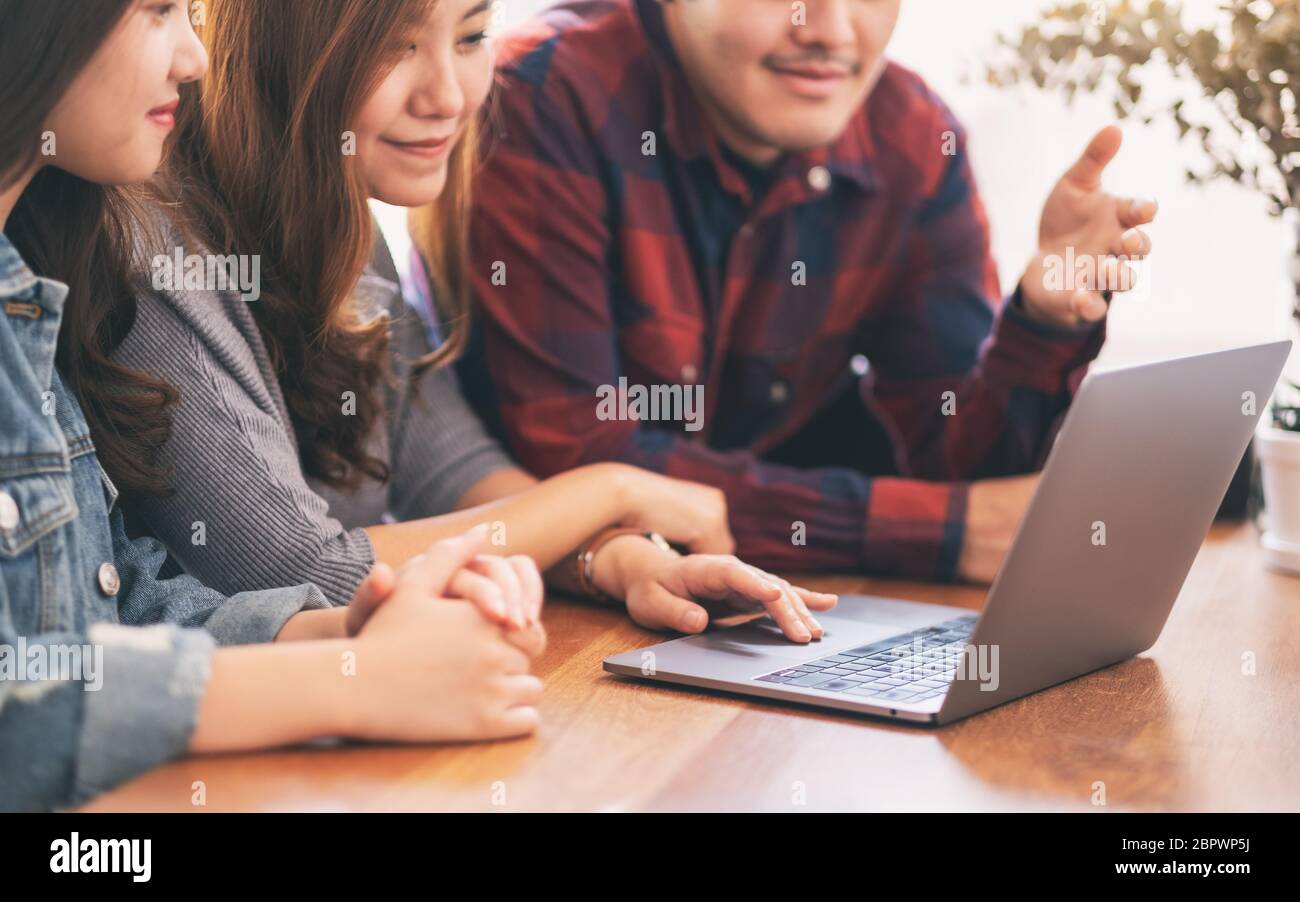 Three young asian people using and looking at the same laptop computer ...