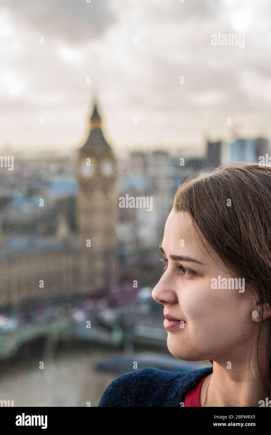 Young beautiful cute girl looks while standing in a ferris wheel cabin ...