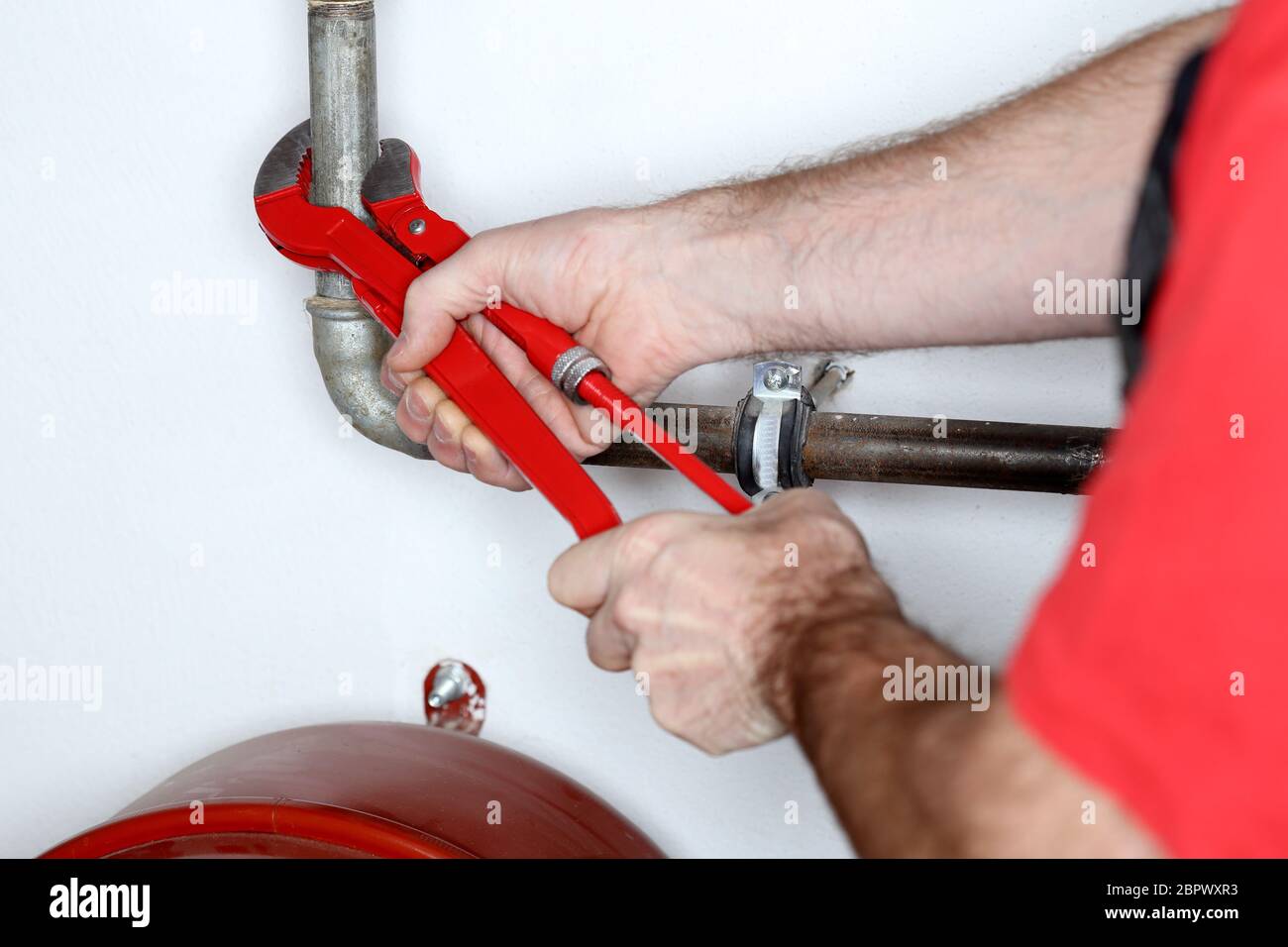 repair man with pincer is instaling a pipe Stock Photo - Alamy