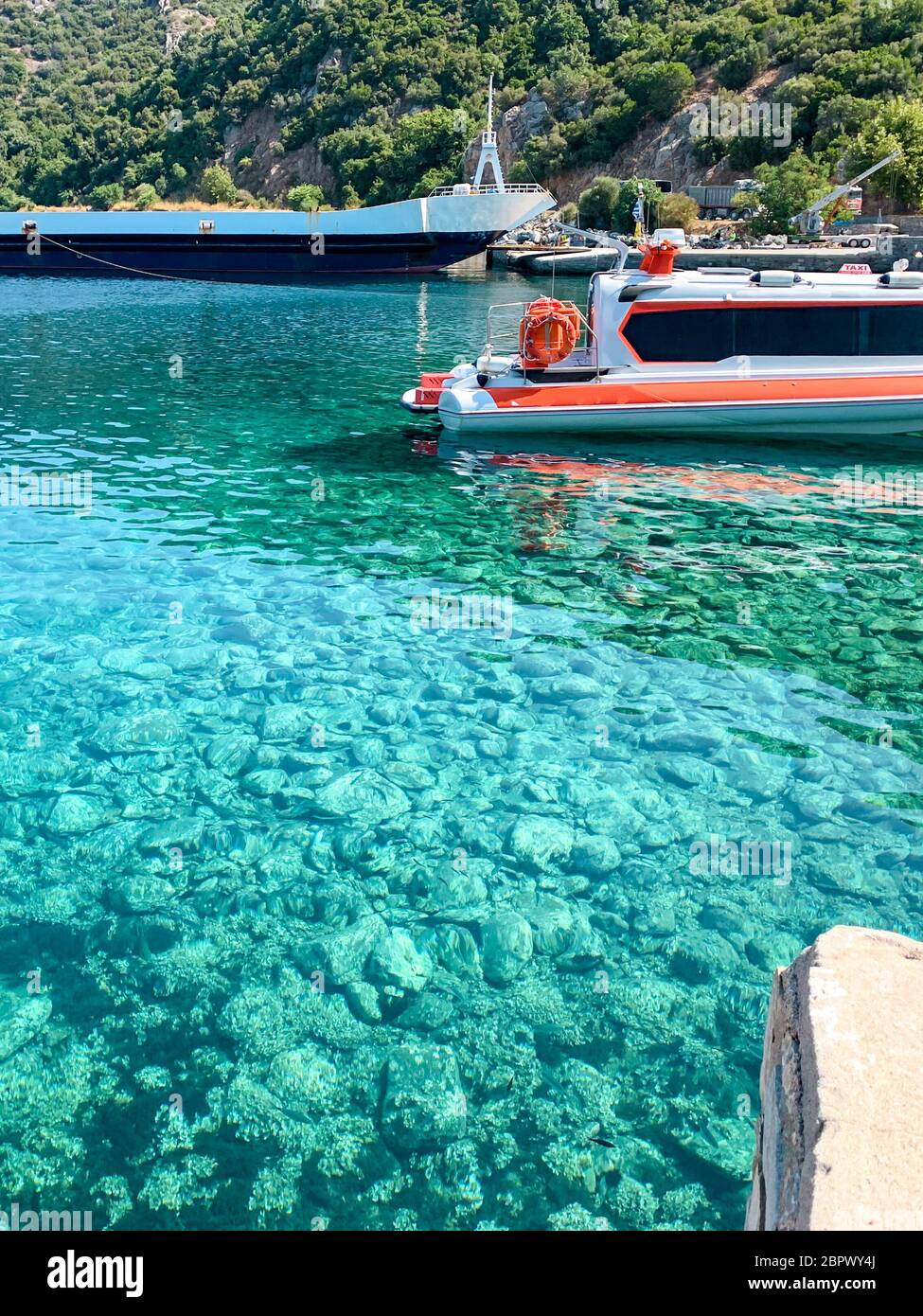 A pier at the foot of Mount Athos in Greece. Clear sea water, a dry ...