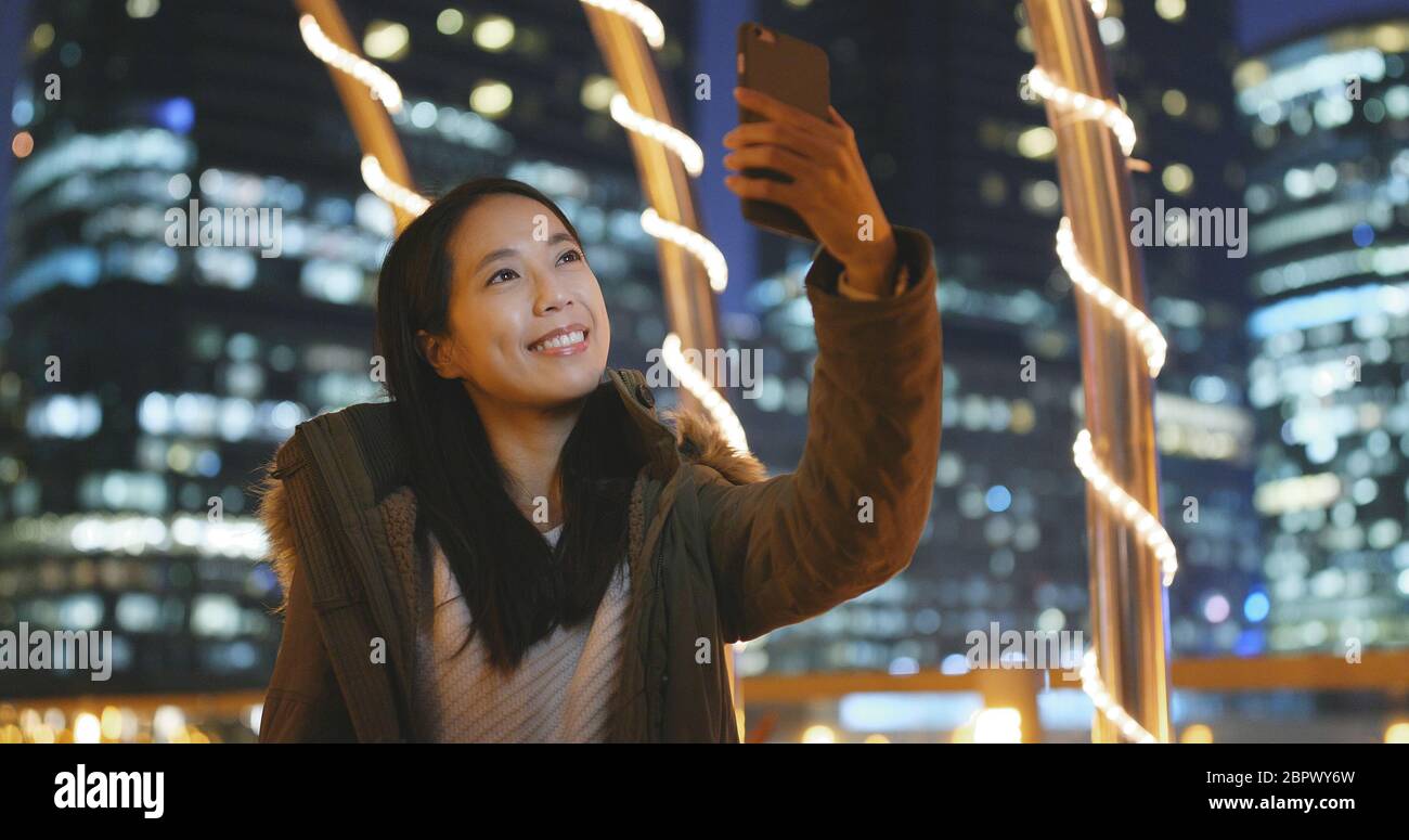 Woman making live stream on cellphone in the city at night, beautiful ...